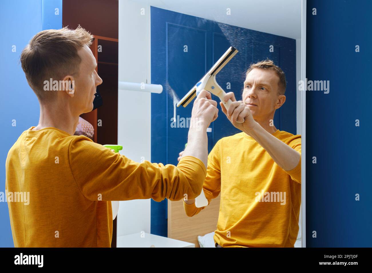 Middle-aged man cleaning mirror at home with rubber mop Stock Photo - Alamy