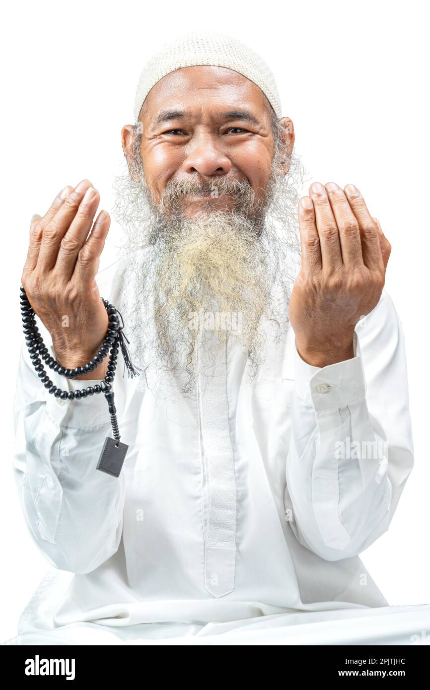 Muslim man with a beard wearing a white cap praying with prayer beads ...