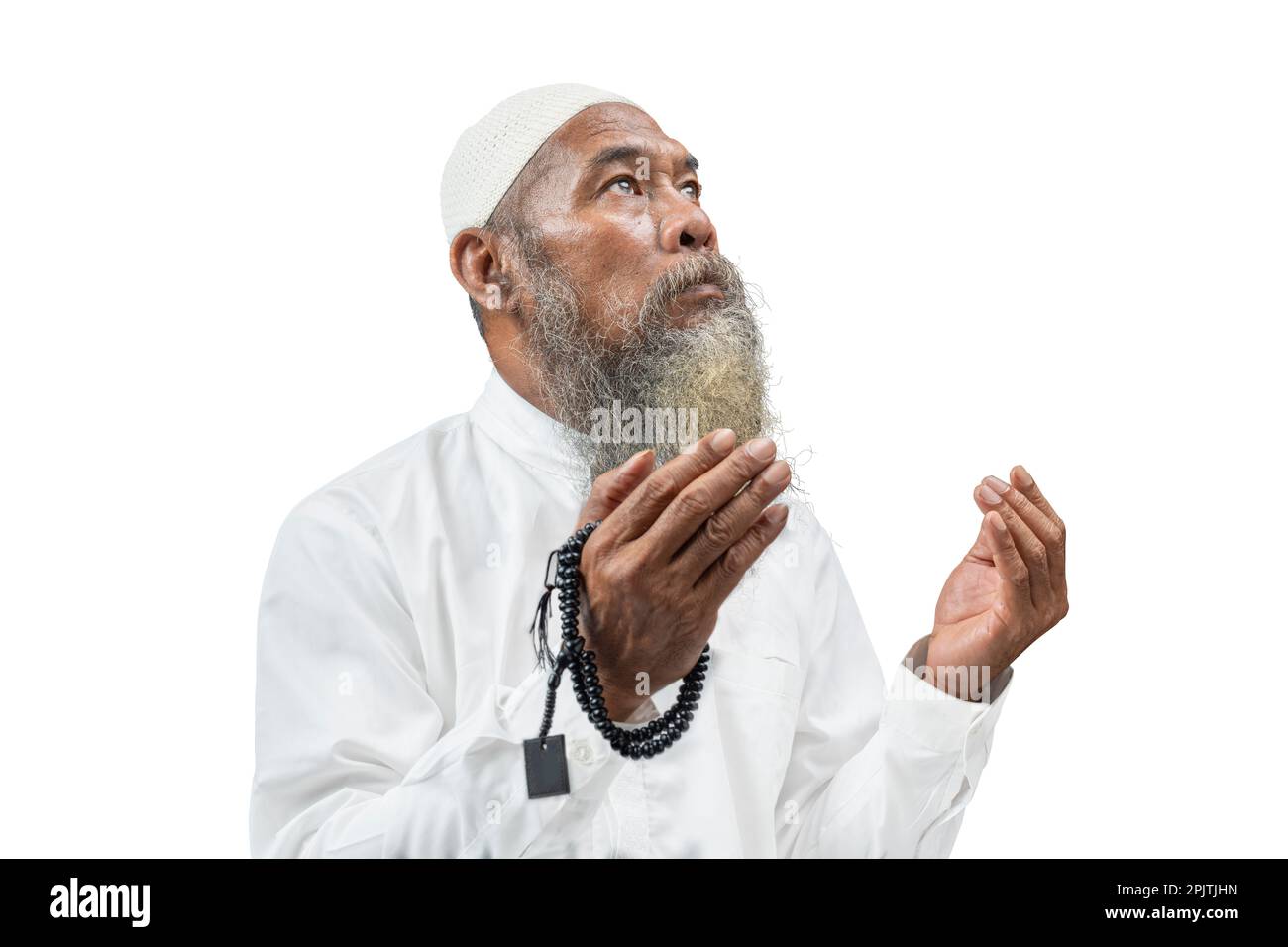 Muslim man with a beard wearing a white cap praying with prayer beads ...