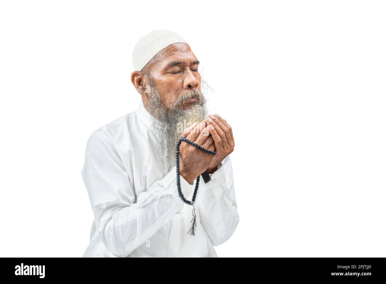 Muslim man with a beard wearing a white cap praying with prayer beads ...