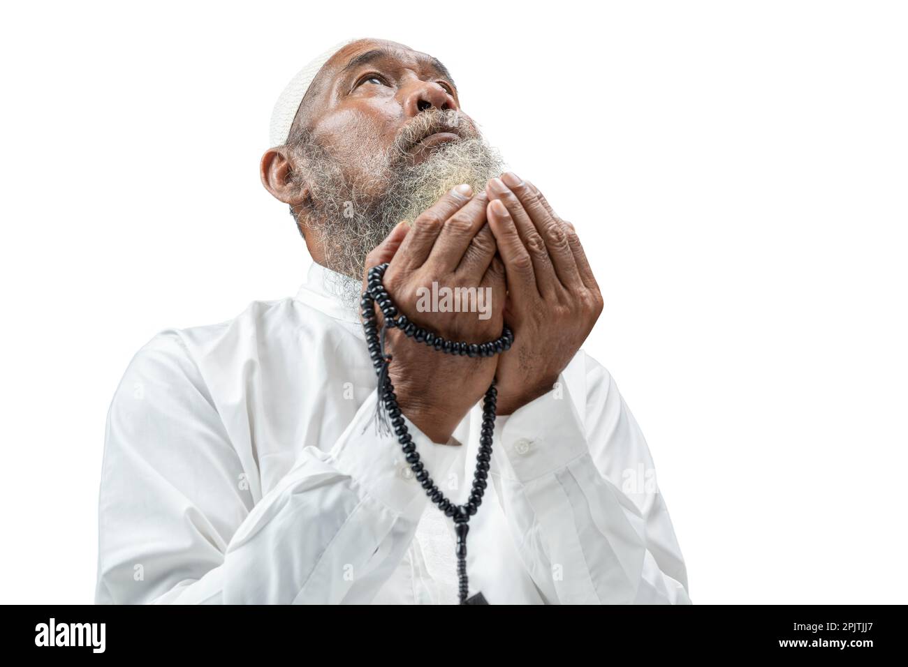 Muslim man with a beard wearing a white cap praying with prayer beads ...