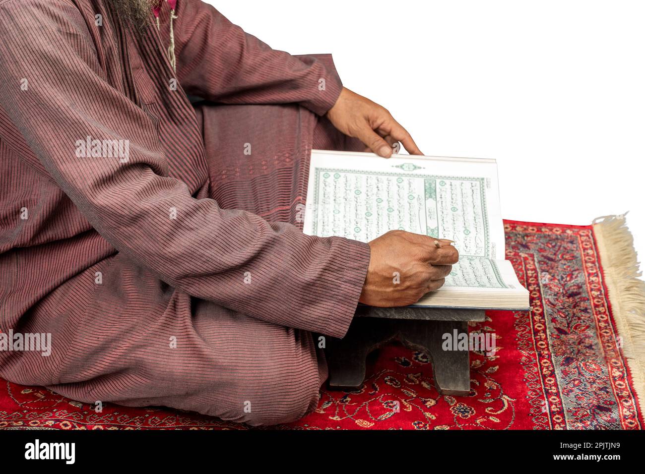 Muslim man sitting and reading the Quran on the prayer rug isolated ...