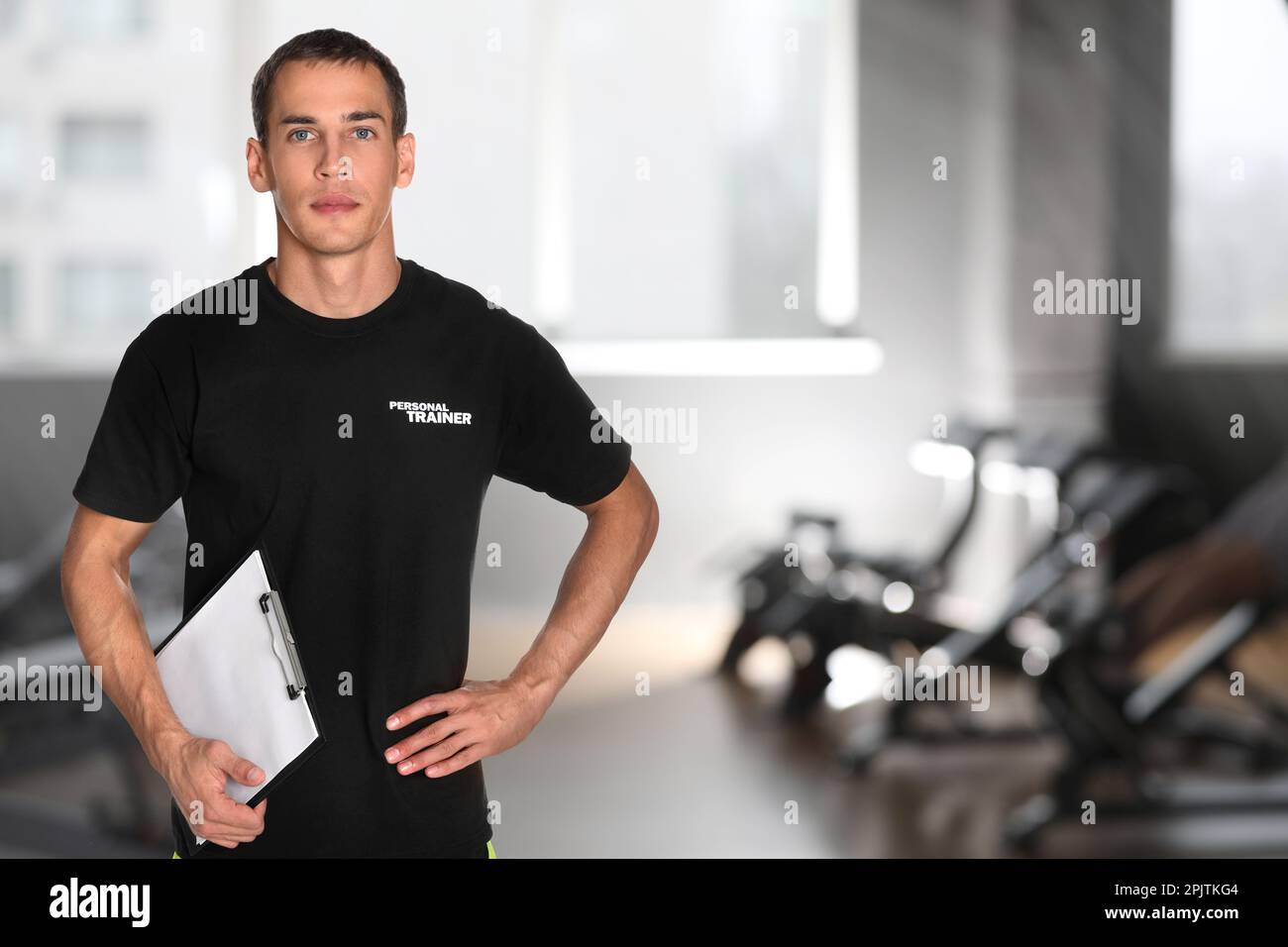 Portrait of professional personal trainer with clipboard in gym. Space ...