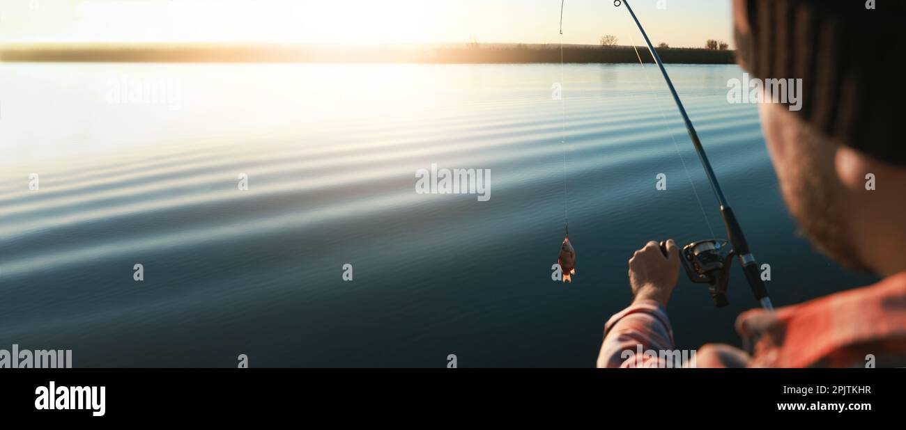 Fisherman catching fish with rod at riverside, closeup view with space ...