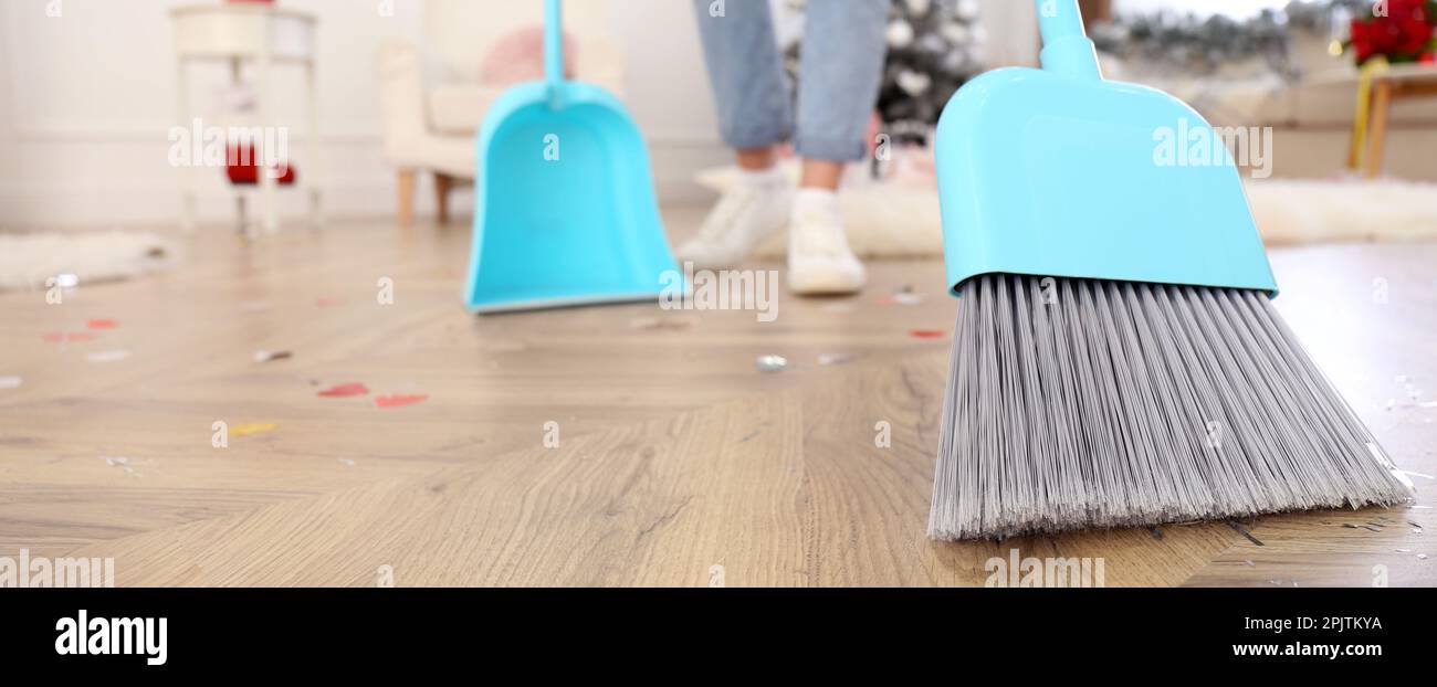 Woman cleaning messy room after New Year party, focus on broom. Banner ...