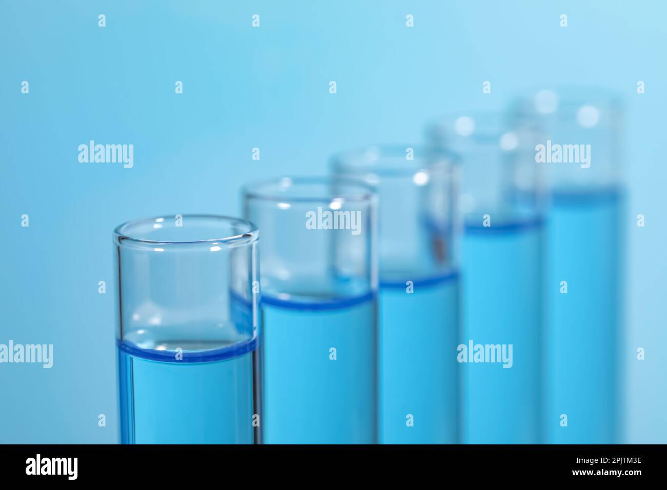 Test tubes with reagents on light blue background, closeup. Laboratory ...