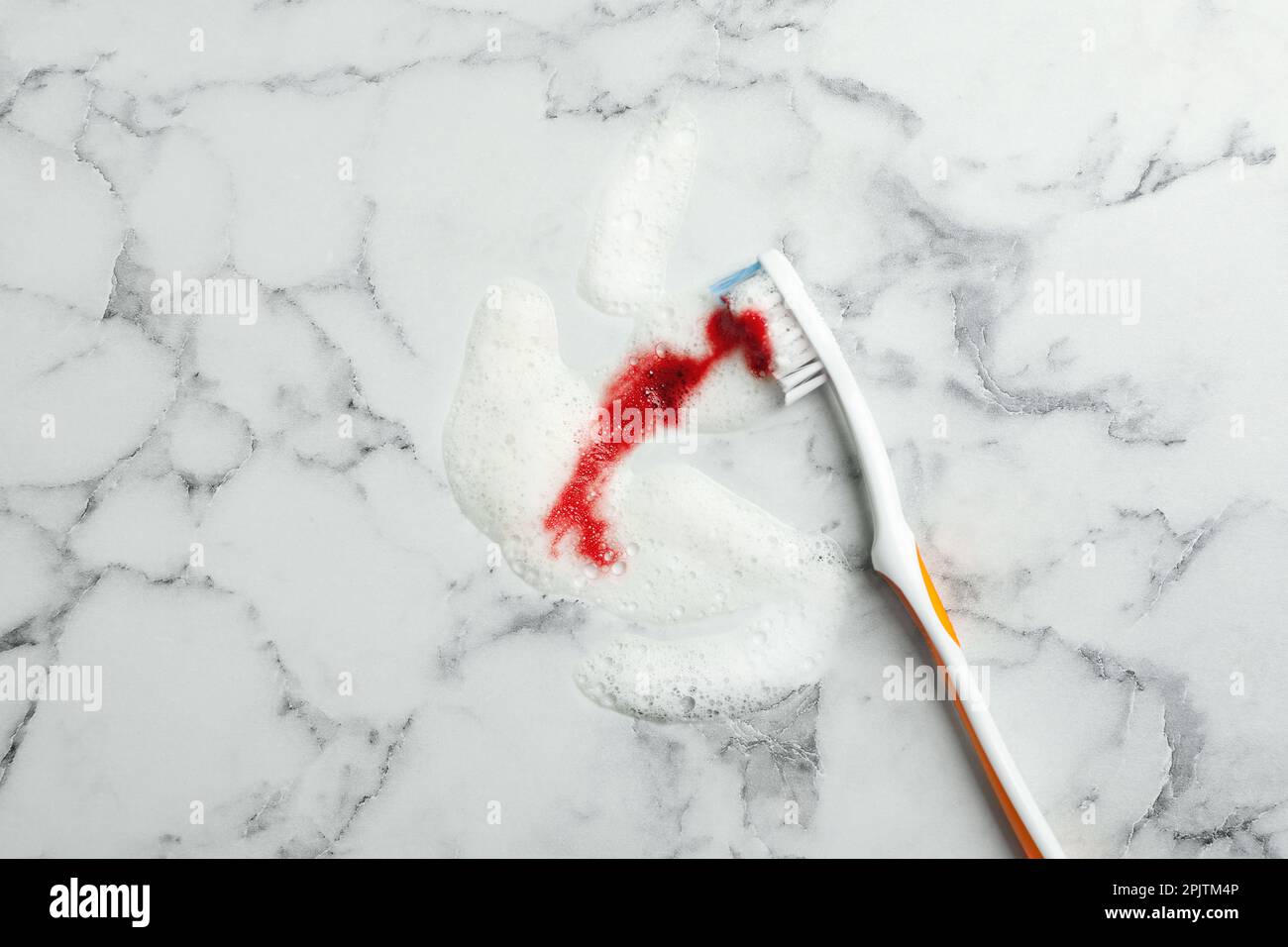 Brush and toothpaste foam with blood on white marble table, top view ...