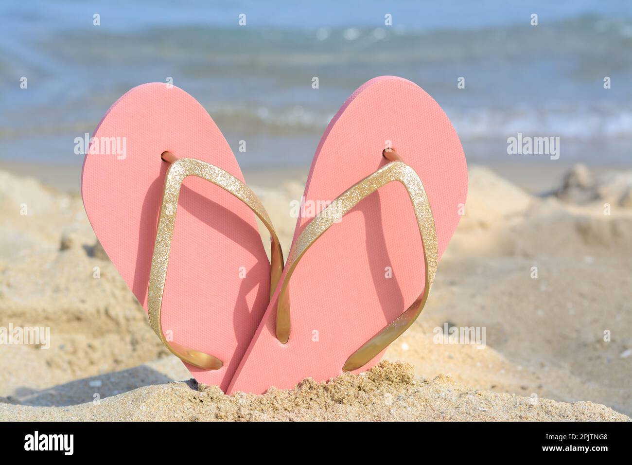 Stylish flip flops in sand on beach near sea Stock Photo - Alamy