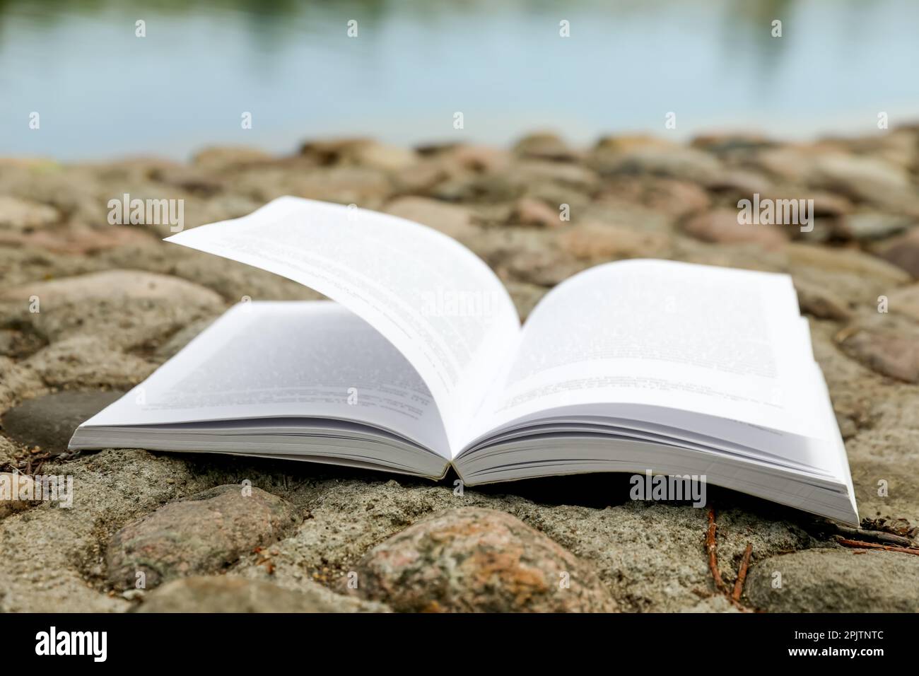Open book on rocky shore near river Stock Photo - Alamy