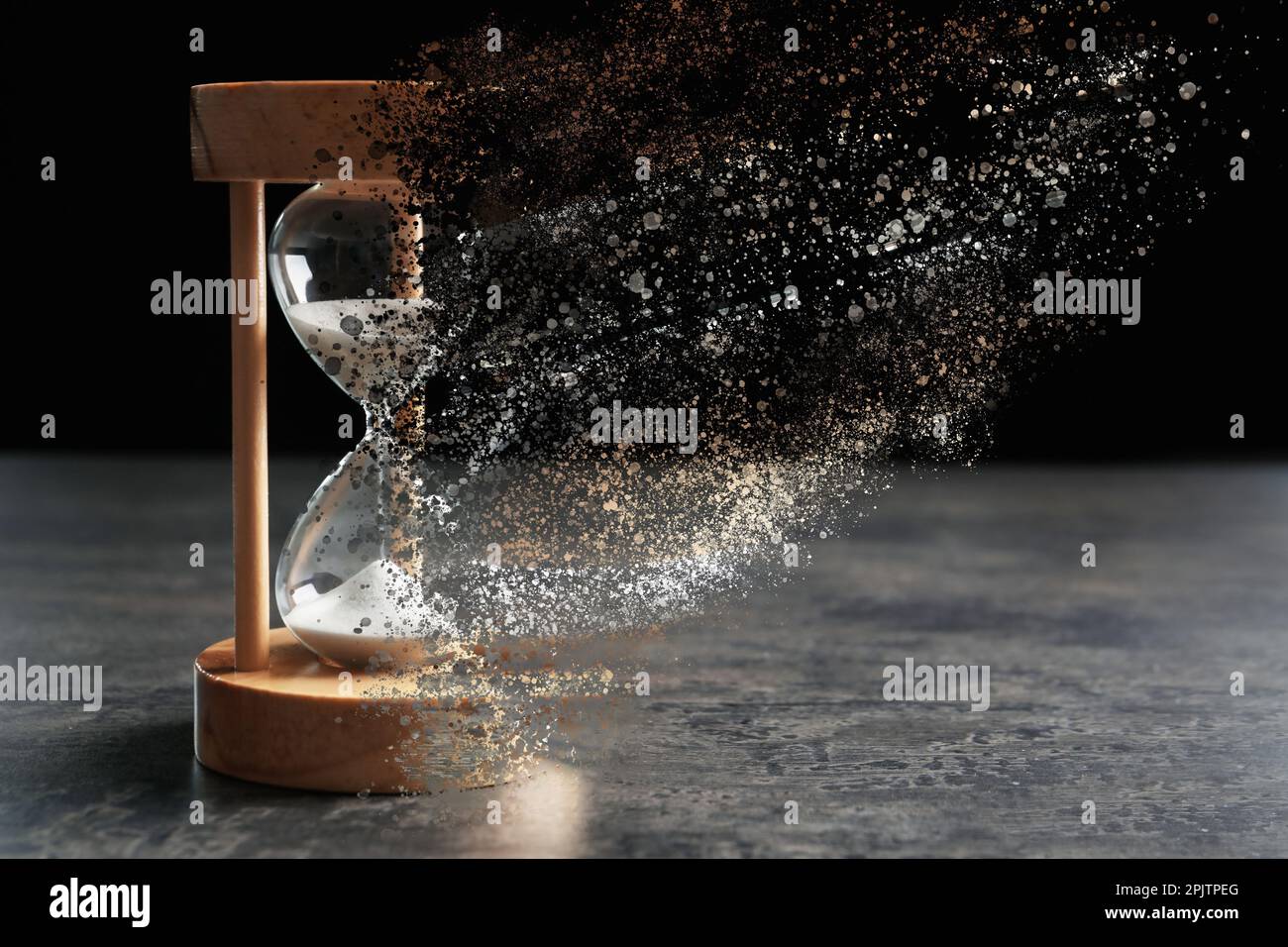Time is running out. Hourglass vanishing on grey table against black ...