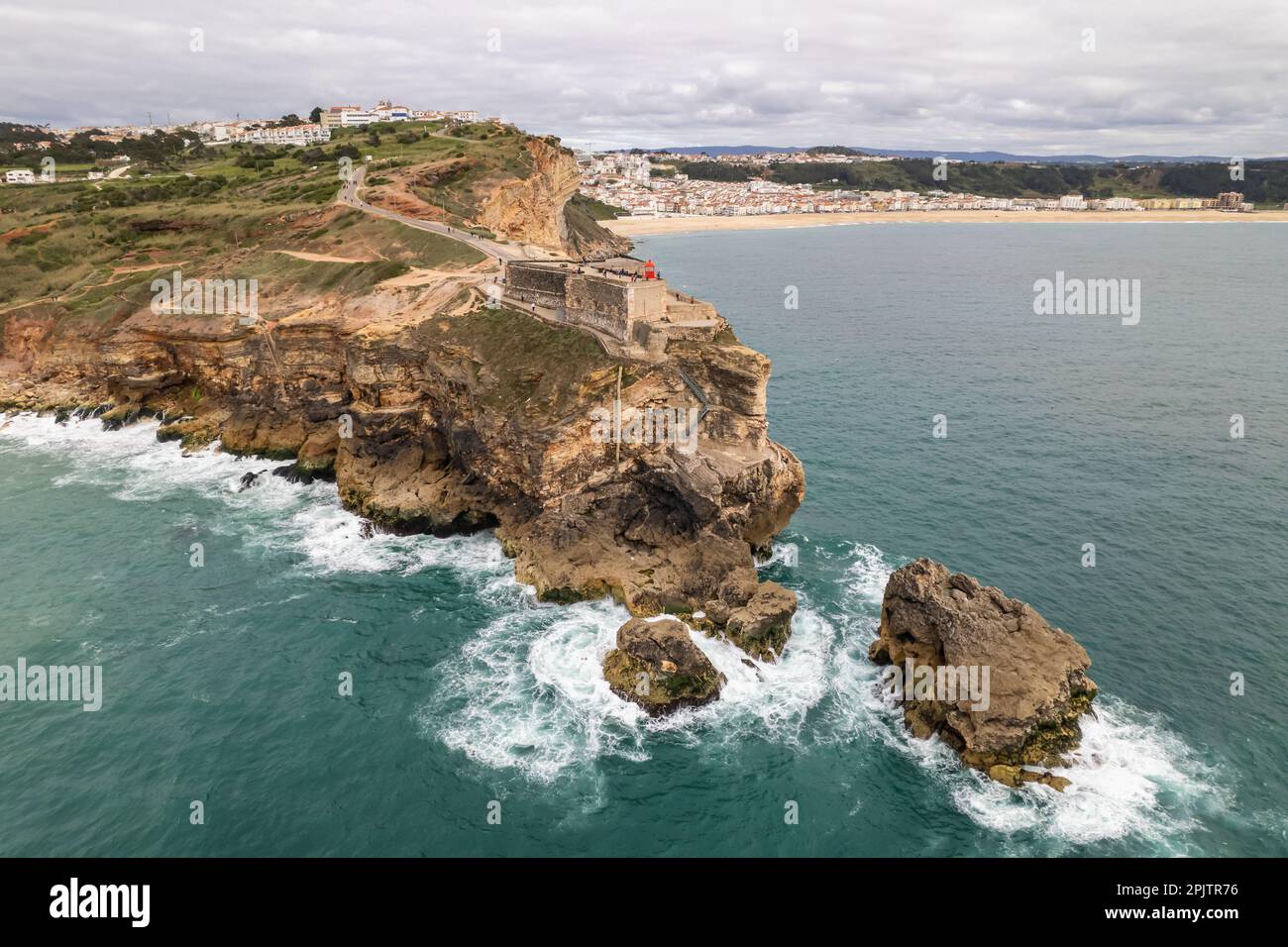 Aerial view of a lighthouse on a cliff with a fortress in Nazare town ...