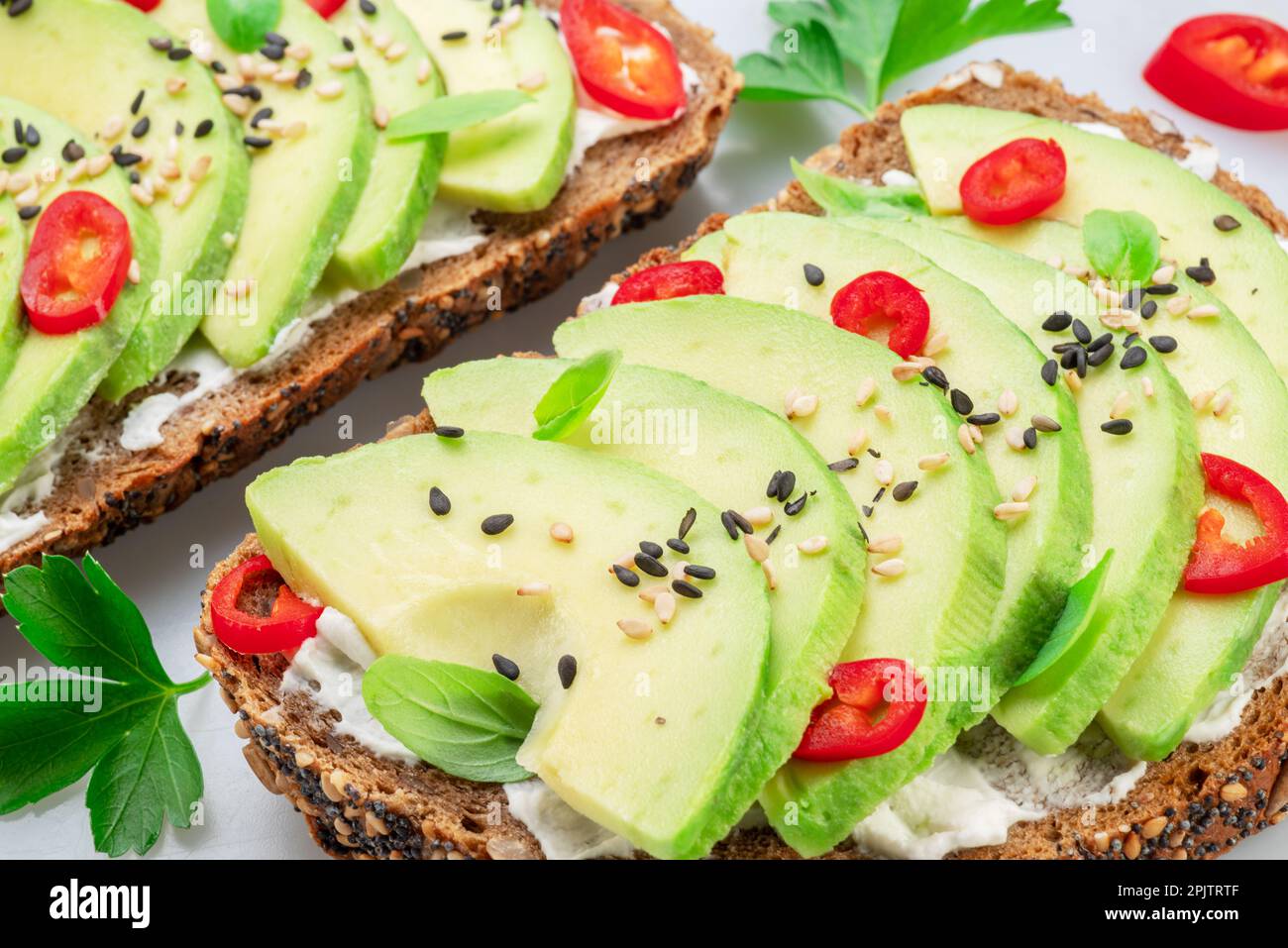 Avocado toasts - bread with avocado slices, pieces of chilli pepper and ...