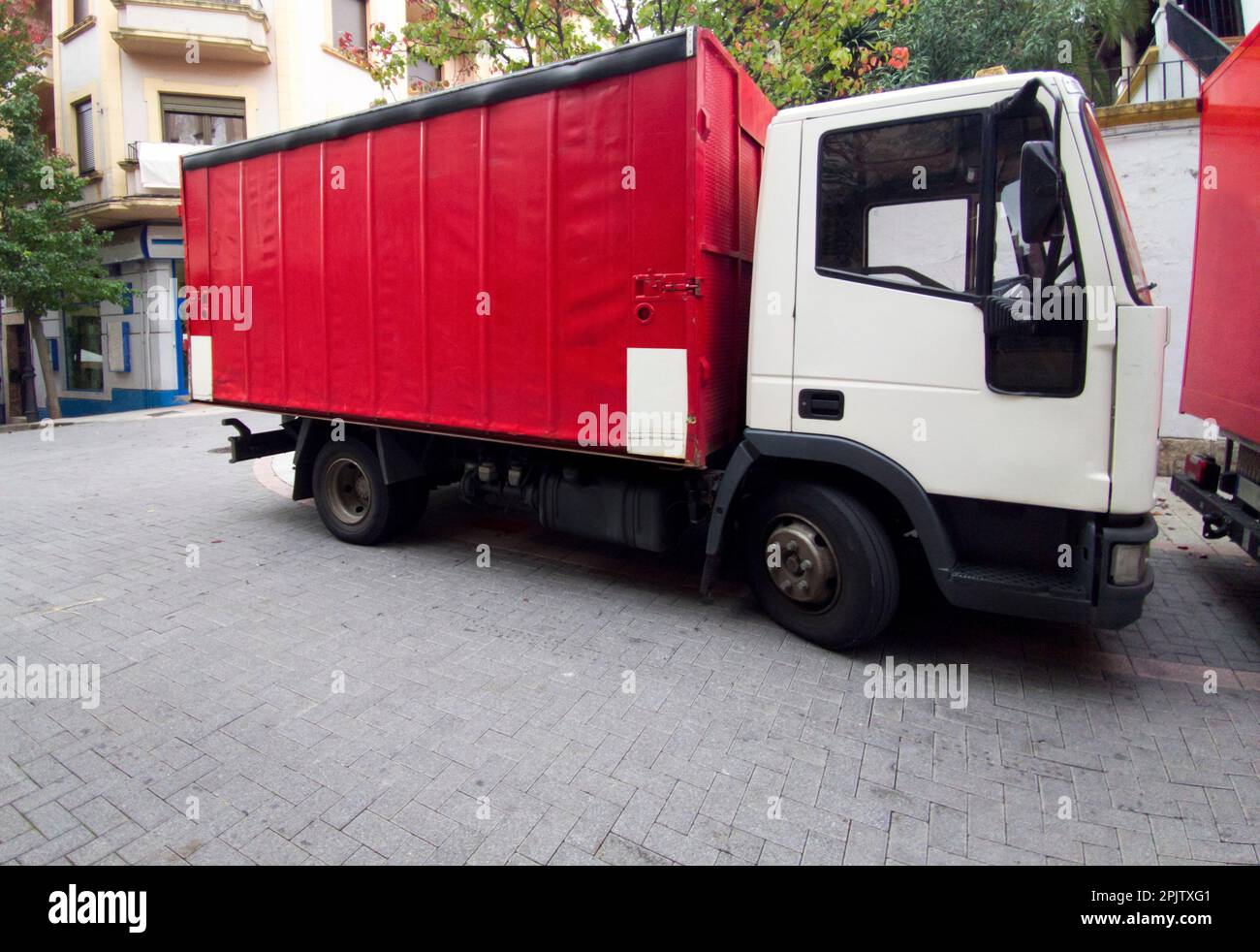 Red semi-trailer trucks parked at city center. Beverage distribution ...