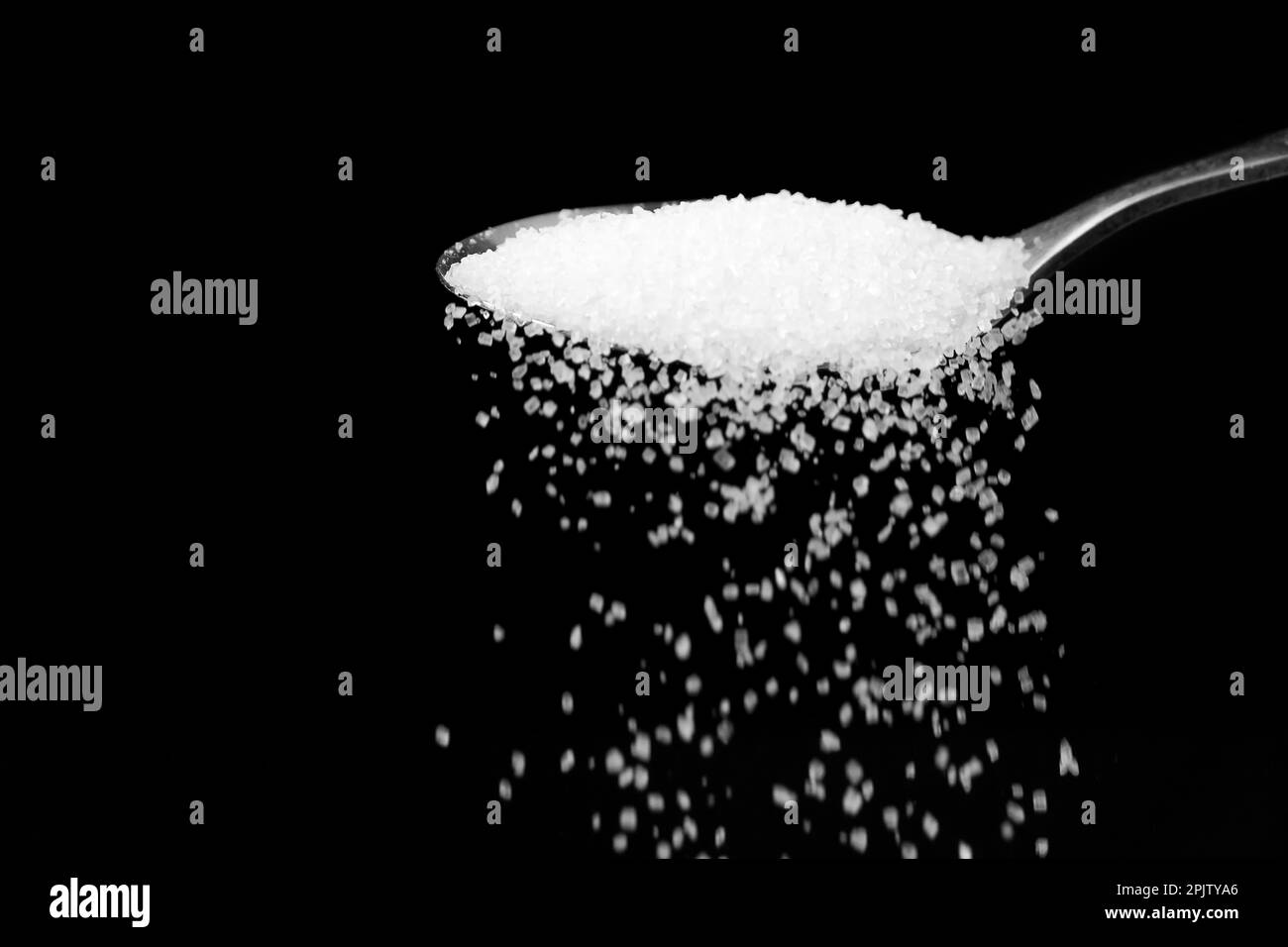 Macro photography of a teaspoon with crumbling white sugar on a black ...