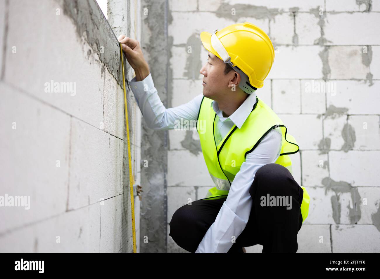Young Asian engineer in engineering uniform and helmet at construction ...