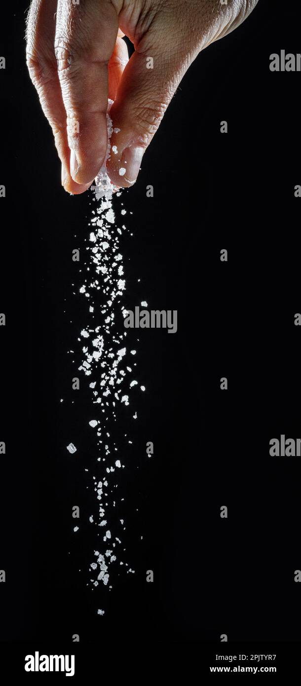 Male hand sprinkling edible salt at black background Stock Photo - Alamy