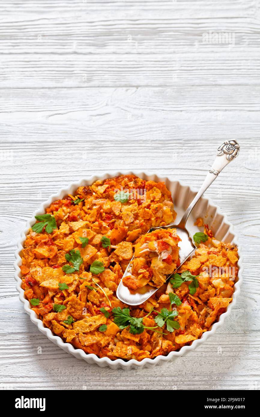 nacho chicken cheese bake in white baking dish with spoon on white wood ...
