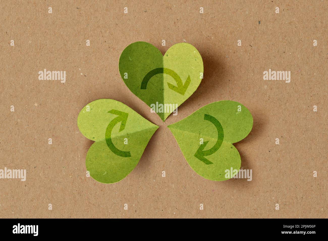 Recycling symbol with heart shaped leaves on recycled paper background ...
