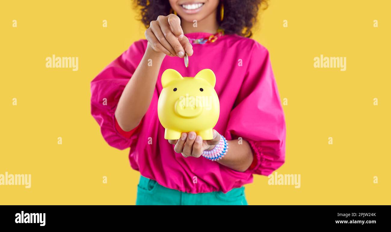 Happy African American child who is saving up money puts coin in little ...