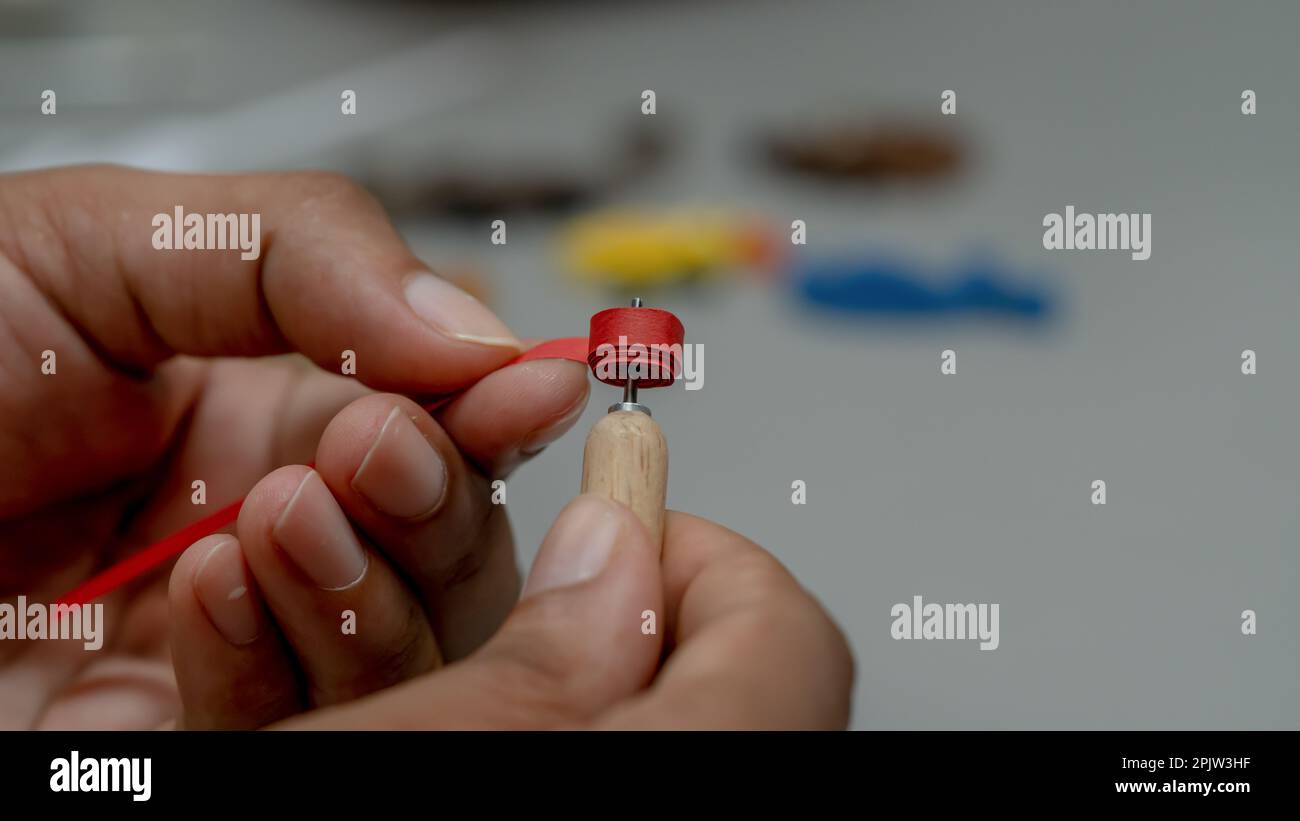 Making a quilling craft with a red paper stripes. Hands with quilling ...