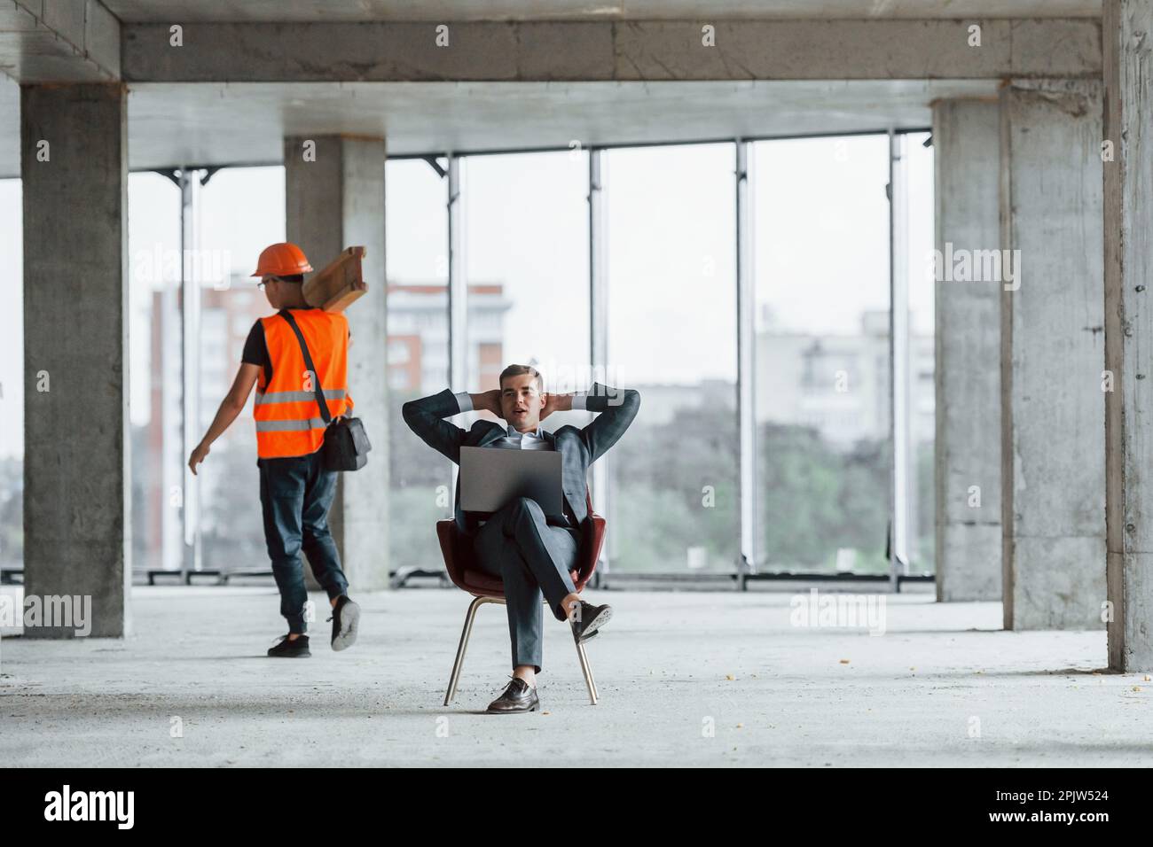 Moving object. Man in suit and handyman in orange protective wear is ...