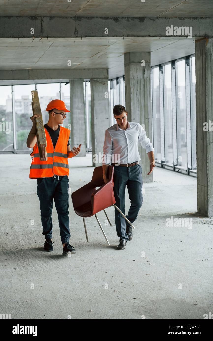Conception of teamwork. Man in suit and handyman in orange protective ...