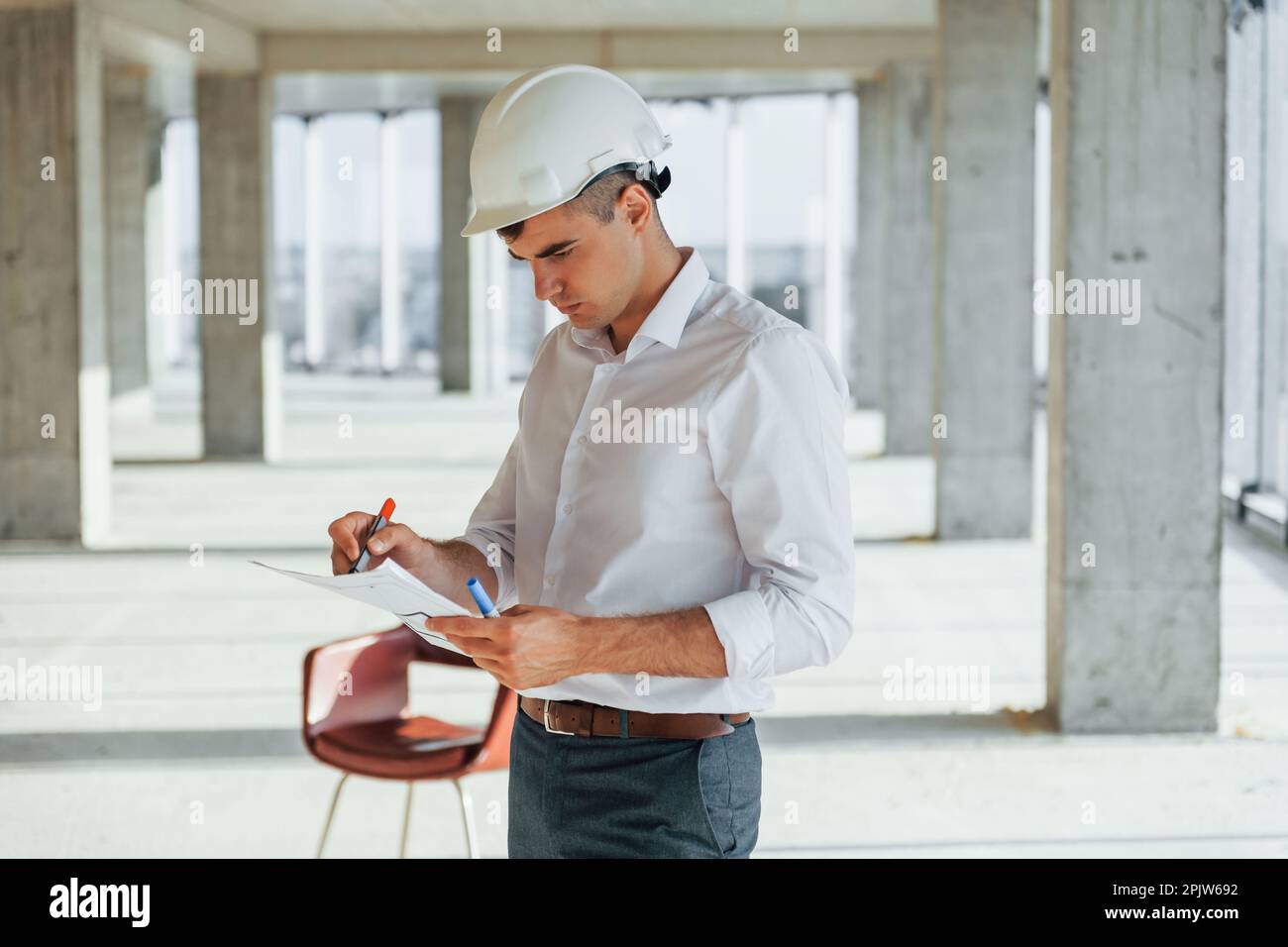Holds documents. Young man in formal wear is working indoors on the ...
