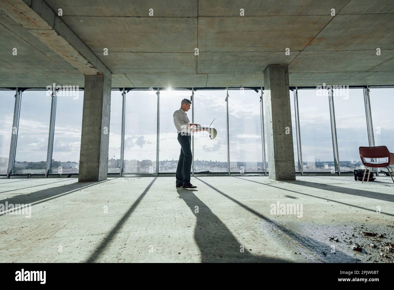Beautiful sunlight goes through big window. Young man in formal wear is ...