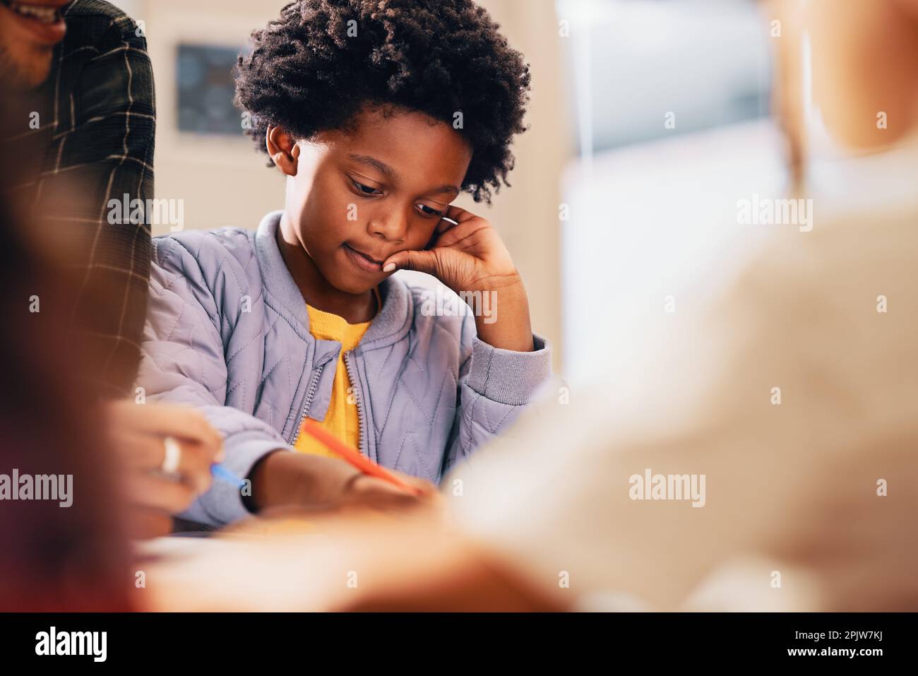 Black kid writing his work in a primary school class. Young boy draws ...