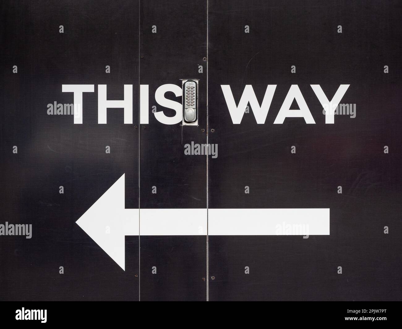This Way sign and an arrow pointing left in bold lettering on a black ...