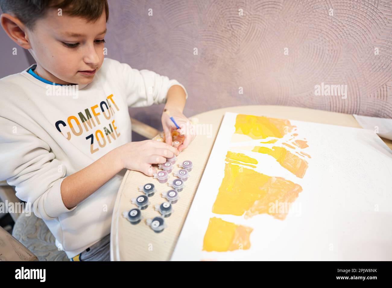 Left handed boy is painting by numbers with gouache at home. Comfort ...