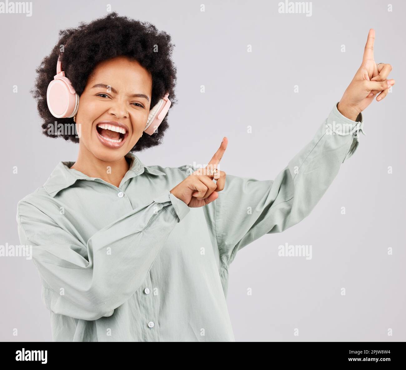 Portrait, music headphones and black woman pointing up in studio ...