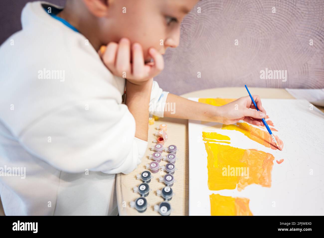 Left handed boy is painting by numbers with gouache at home Stock Photo ...
