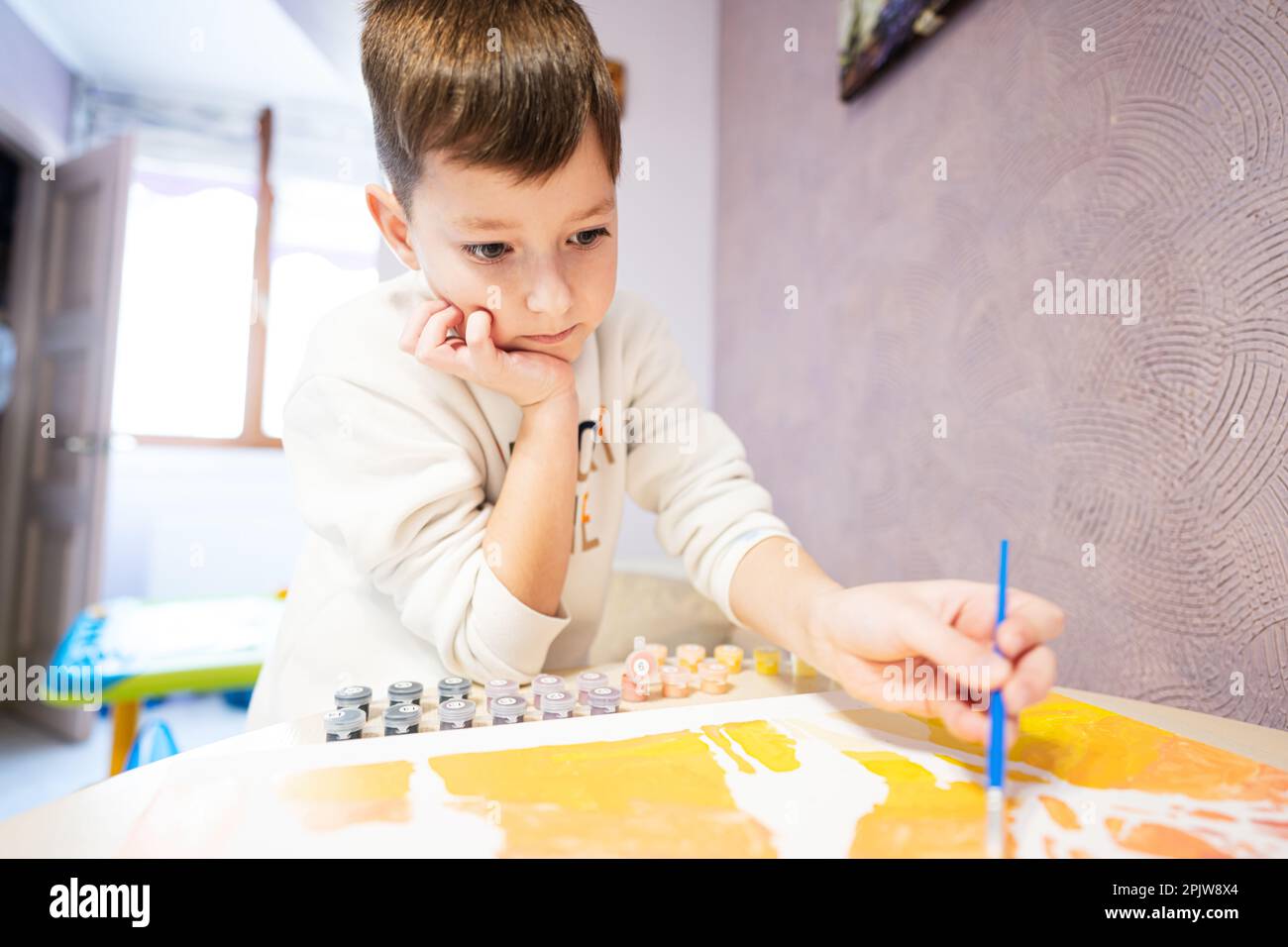 Left handed boy is painting by numbers with gouache at home Stock Photo ...