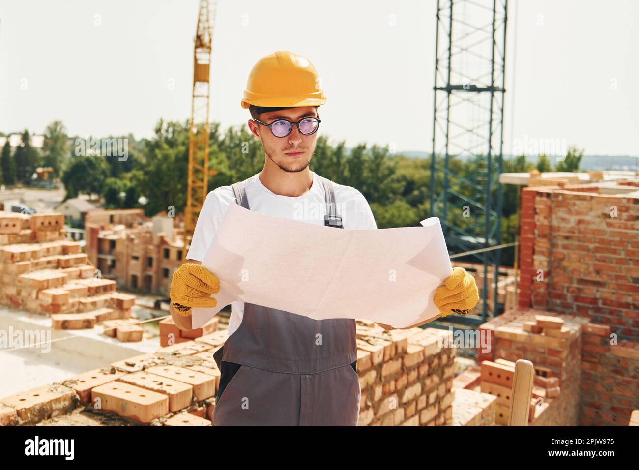 Holding document. Young construction worker in uniform is busy at the ...
