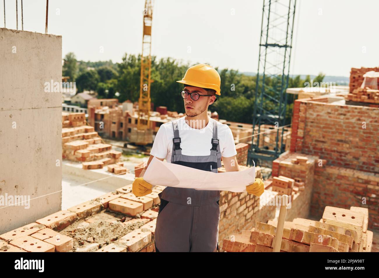 Holding document. Young construction worker in uniform is busy at the ...