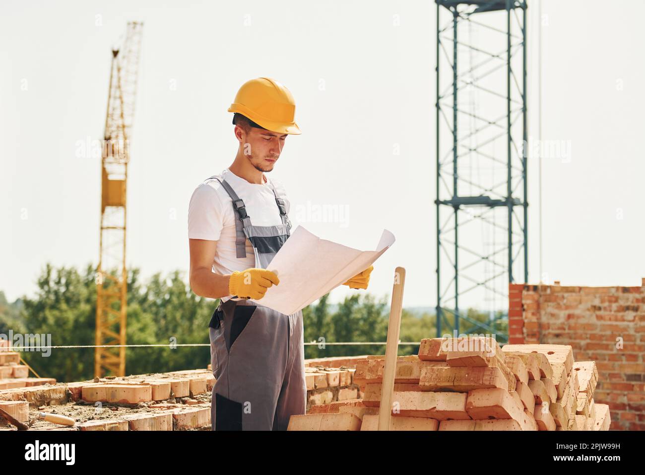 Holding document. Young construction worker in uniform is busy at the ...