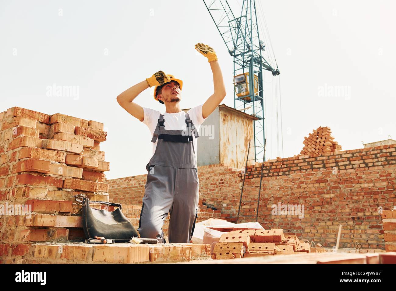 Young construction worker in uniform is busy at the unfinished building ...