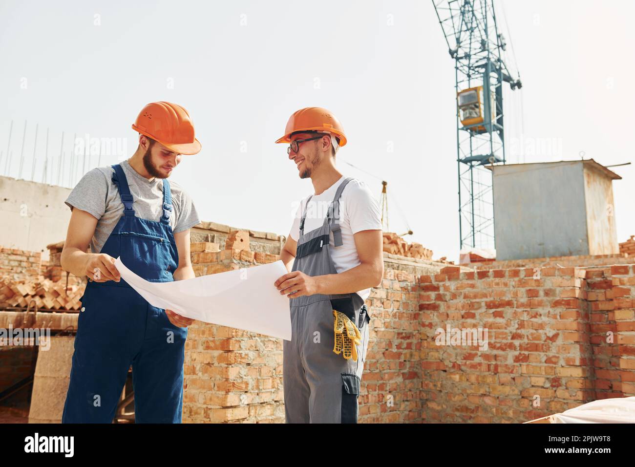 With documents. Two construction workers is together at the building ...