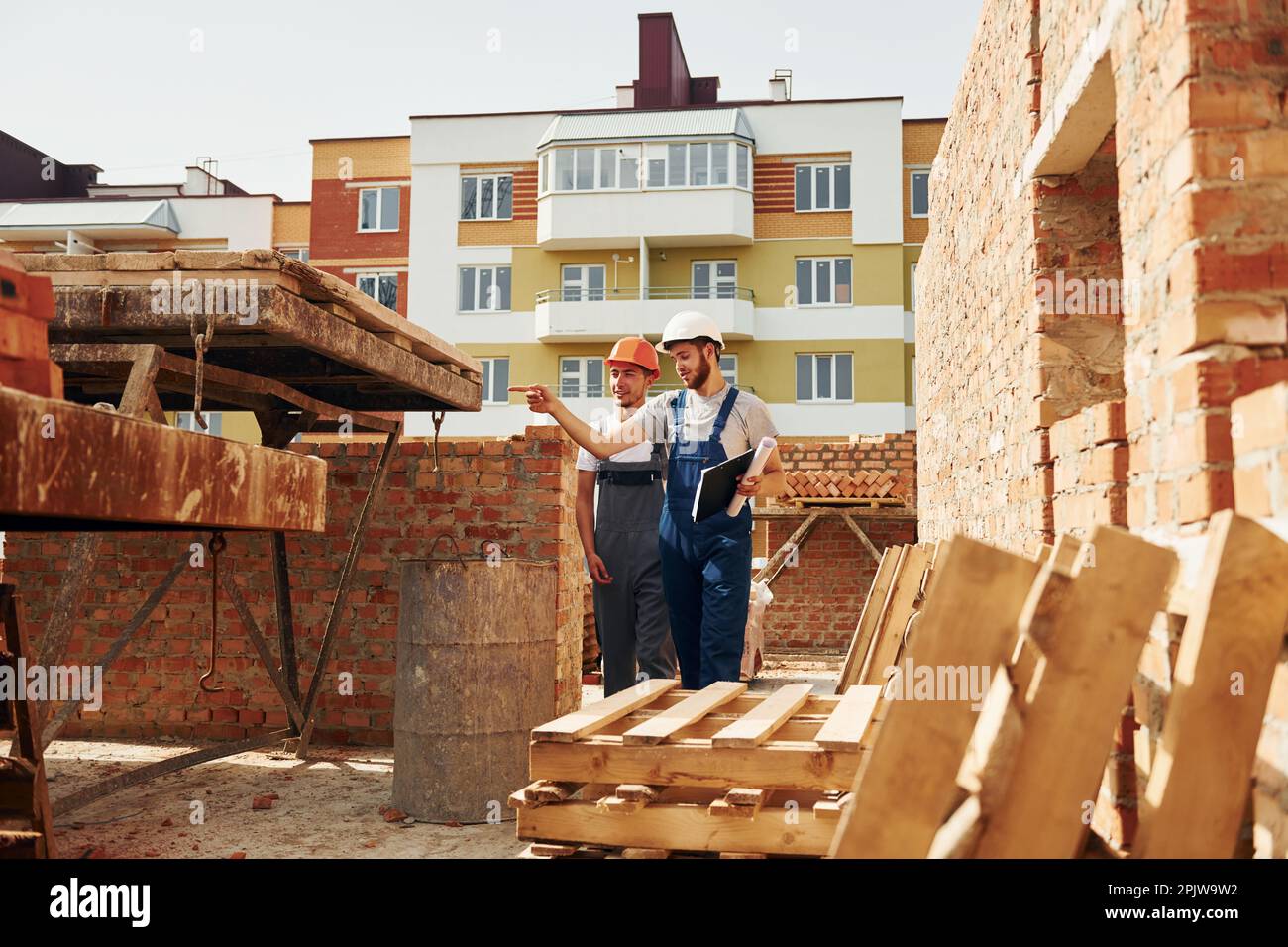 Two construction workers is together at the building Stock Photo - Alamy