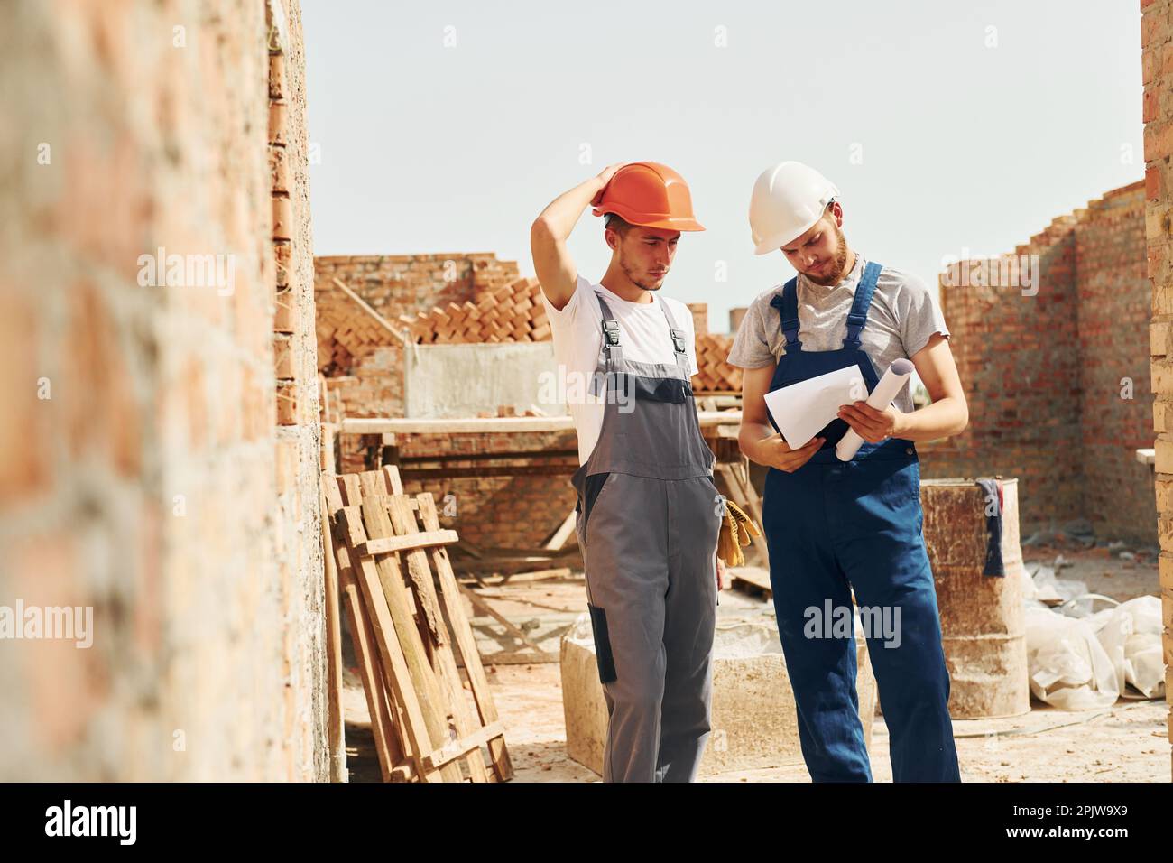 With documents. Two construction workers is together at the building ...