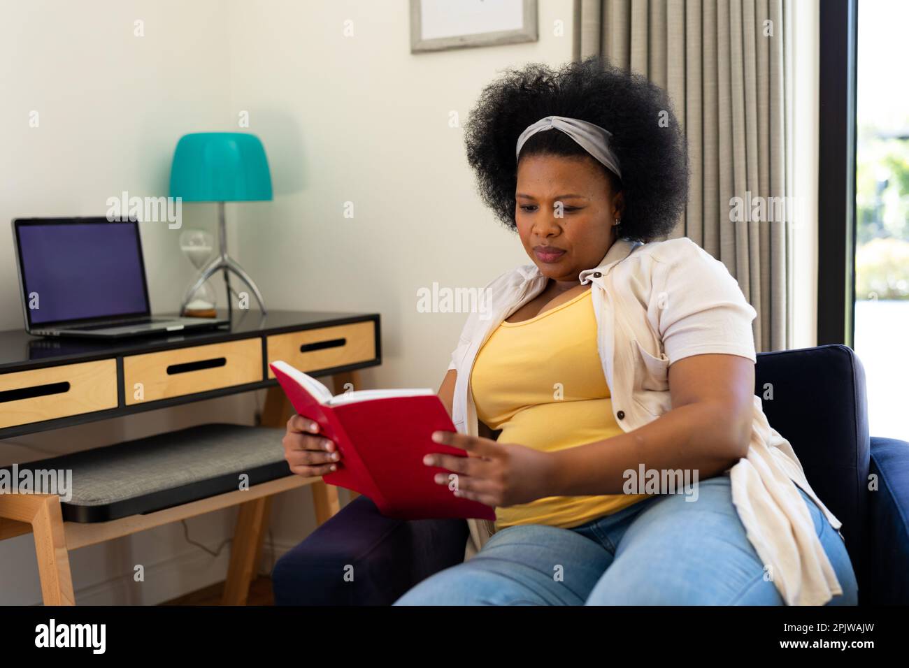 Plus size african american woman sitting in armchair at home ...
