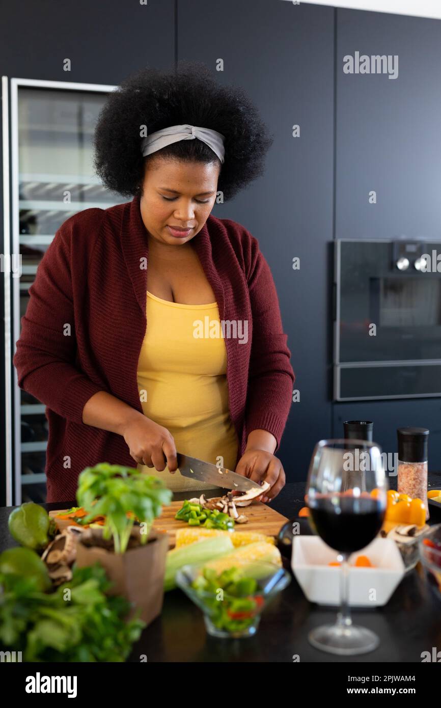 Happy plus size african american woman preparing dinner, chopping vegetables in kitchen Stock ...