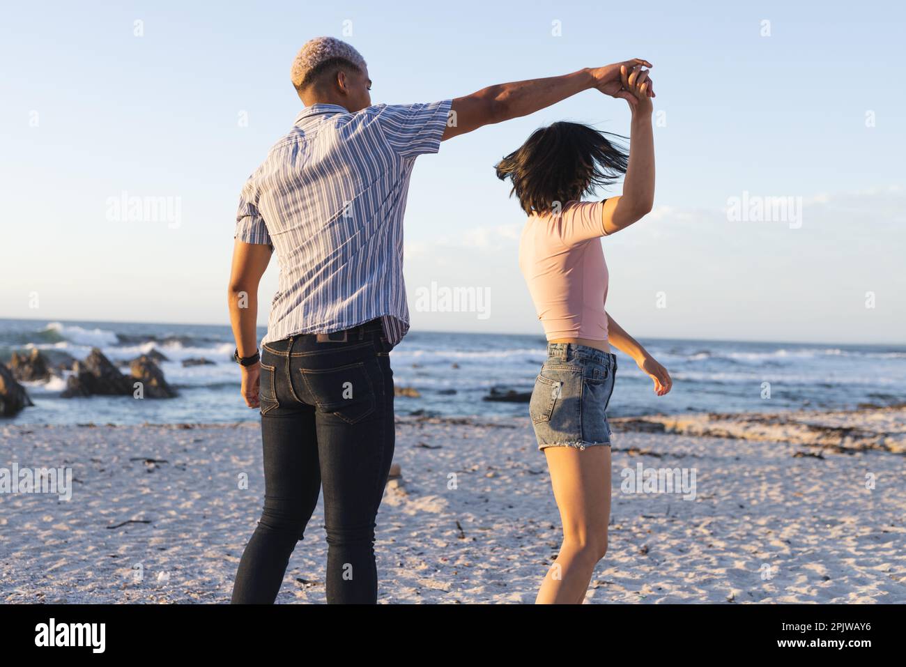 Happy diverse couple holding hands and dancing together at beach Stock ...