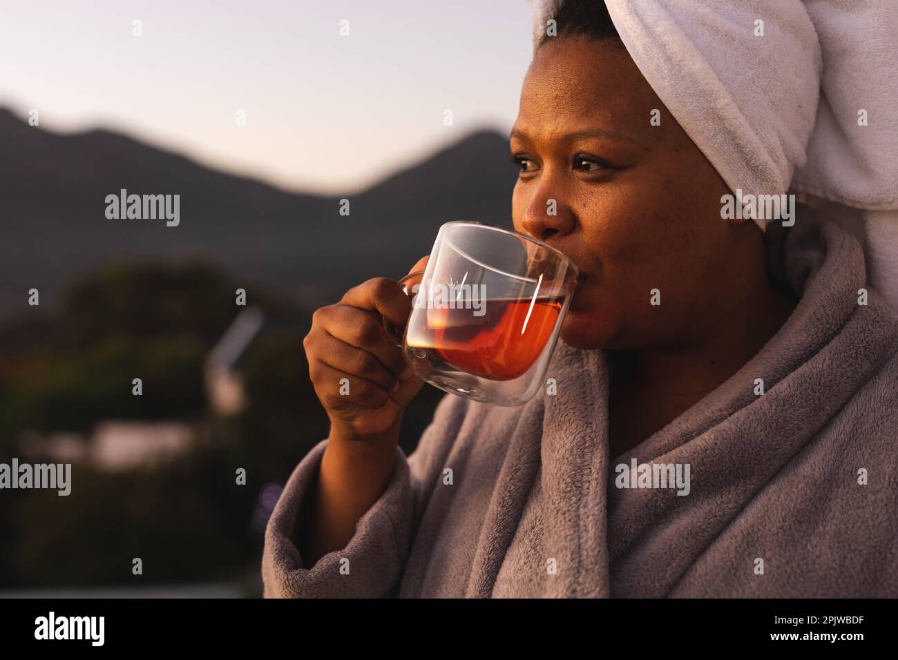 Happy plus size african american woman wearing robe and towel on head ...