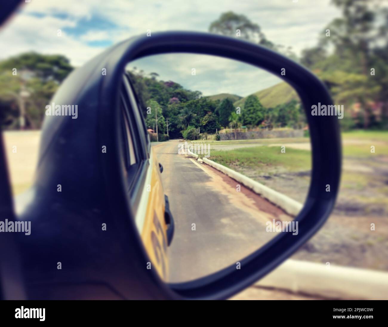 This stock photo features a rear view of a side car mirror reflecting a ...