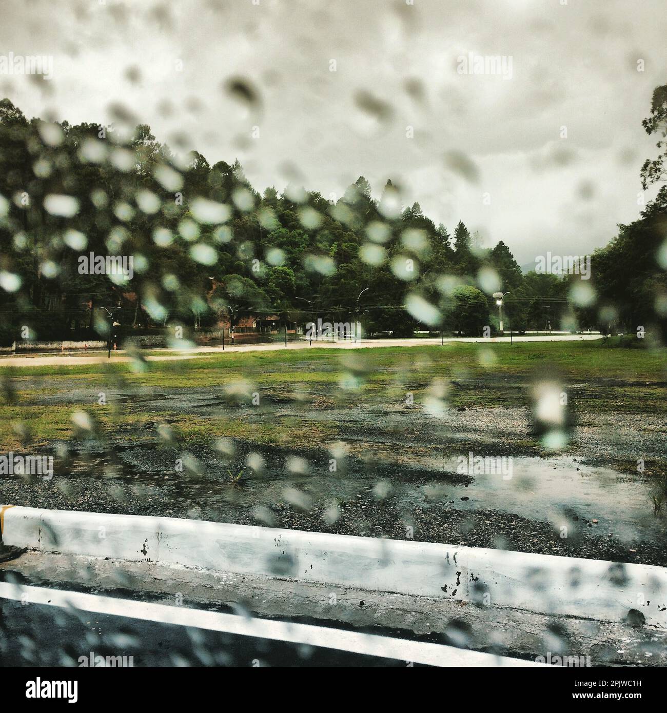 Close-up of a car window with droplets of rain on its surface against a ...
