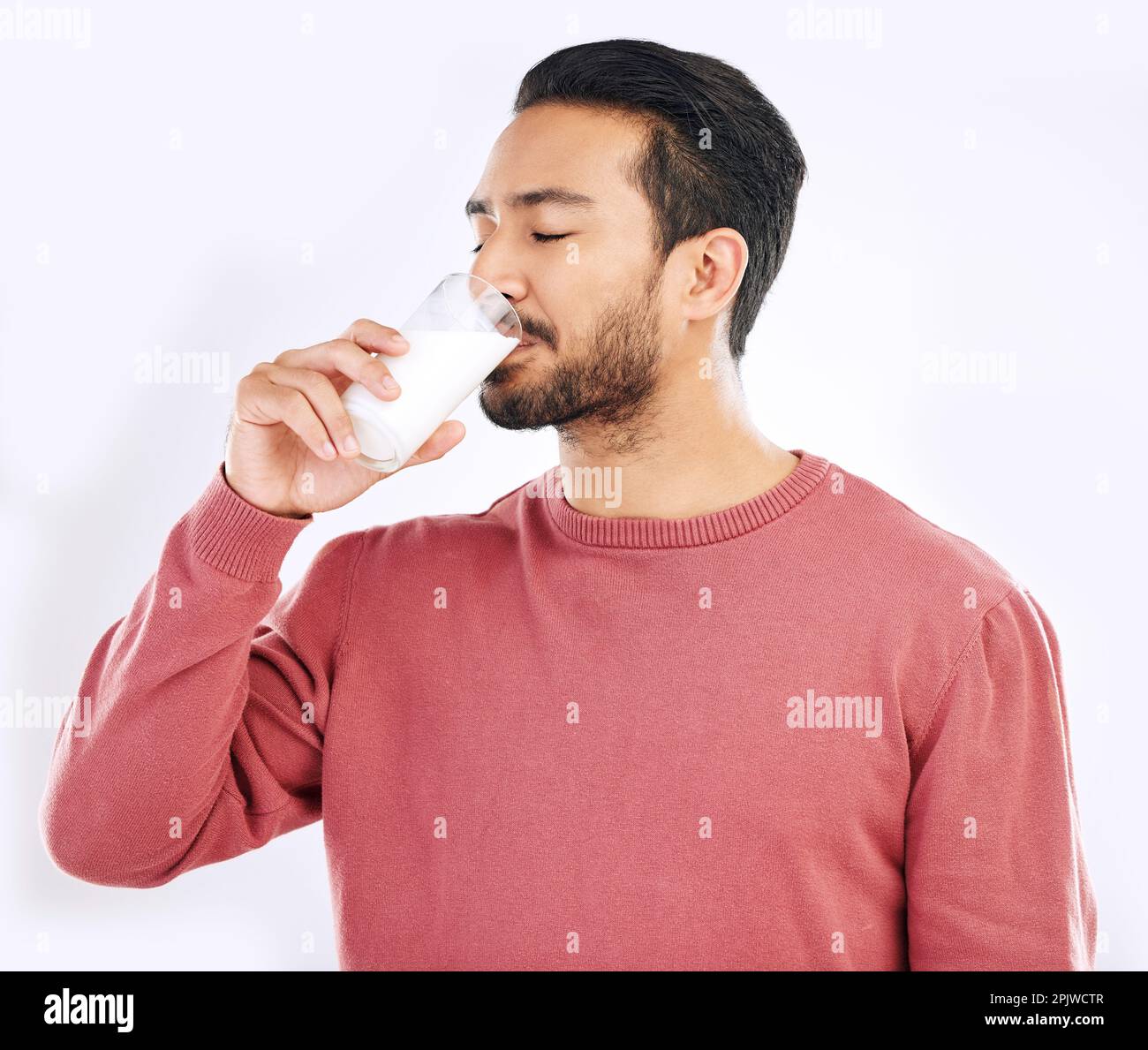 Man drinking glass of milk in studio, white background and backdrop for ...