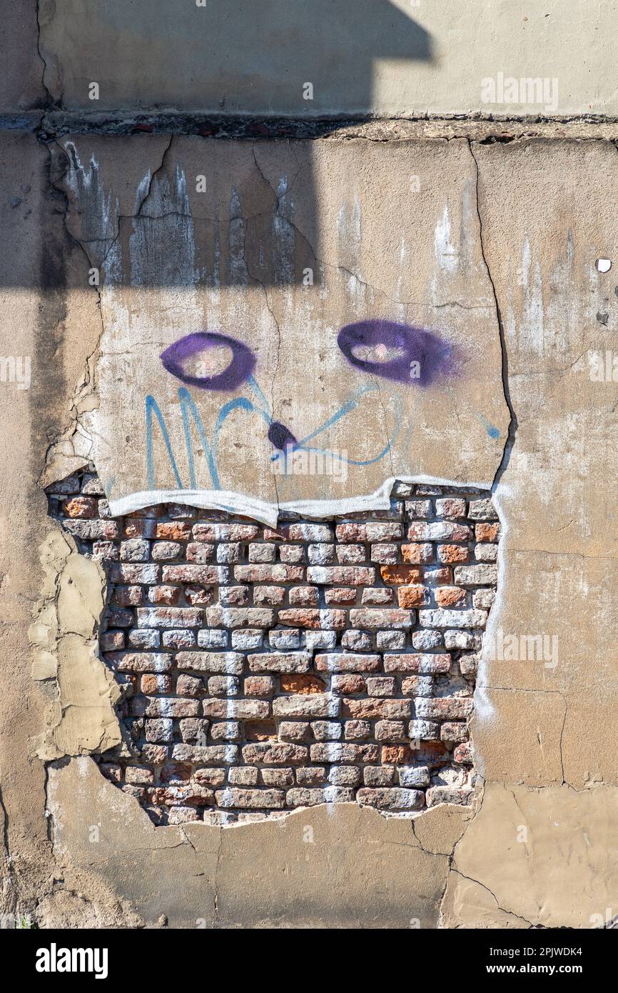 Dilapidated wall marked with a tag transforming it into a face ...