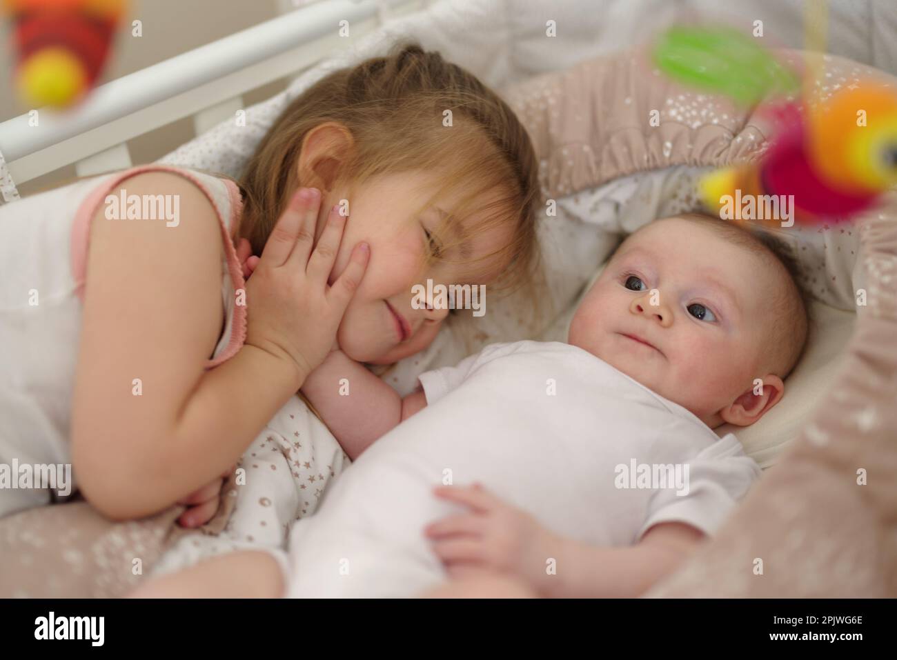 Close up of a cute little girl playing with his baby brother in the ...